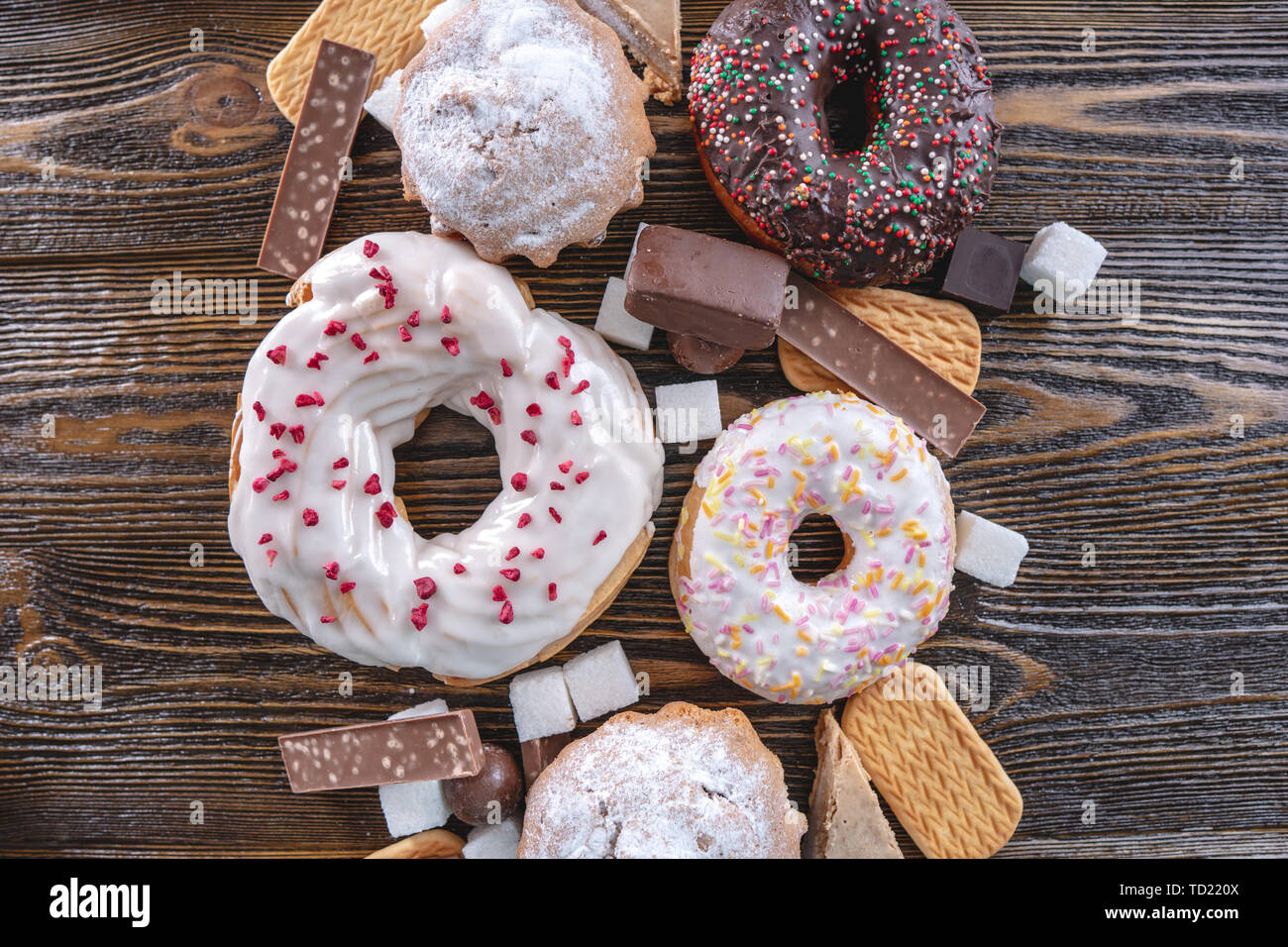 Harmful sweet foods on a dark wooden background. Donuts, muffins ...