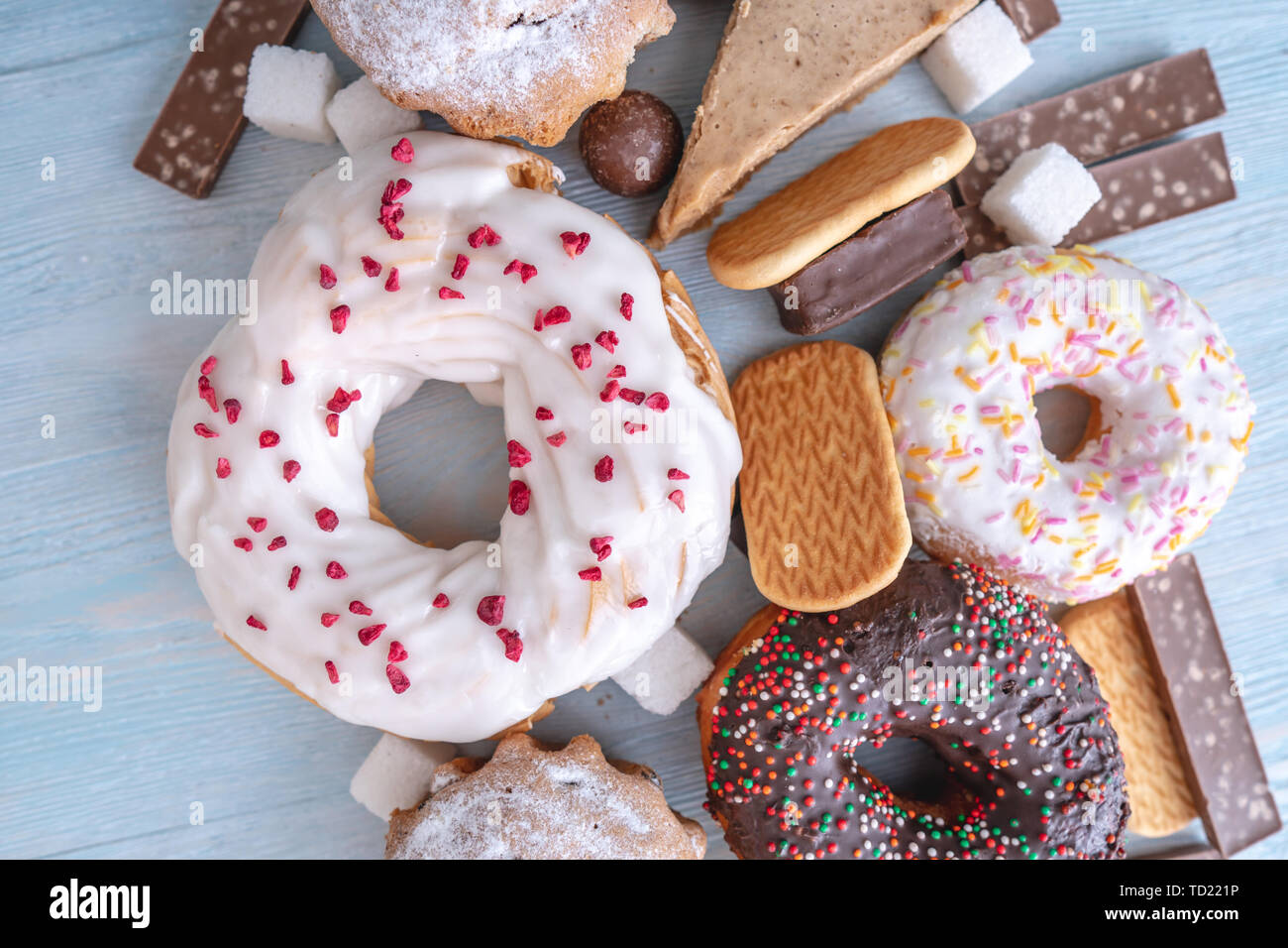 Harmful sweet foods on blue wooden background. Donuts, muffins ...