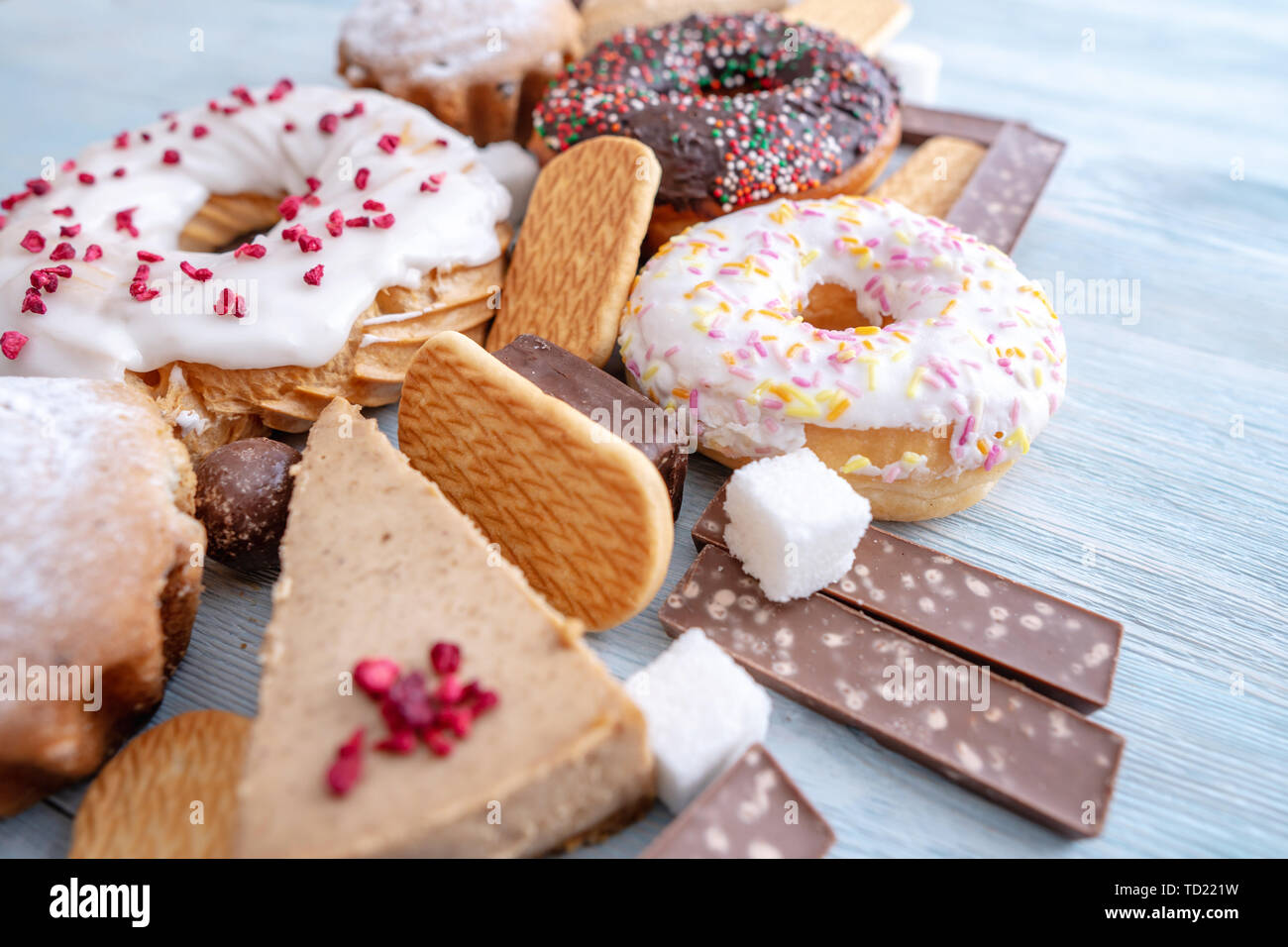 Harmful sweet foods on blue wooden background. Donuts, muffins ...