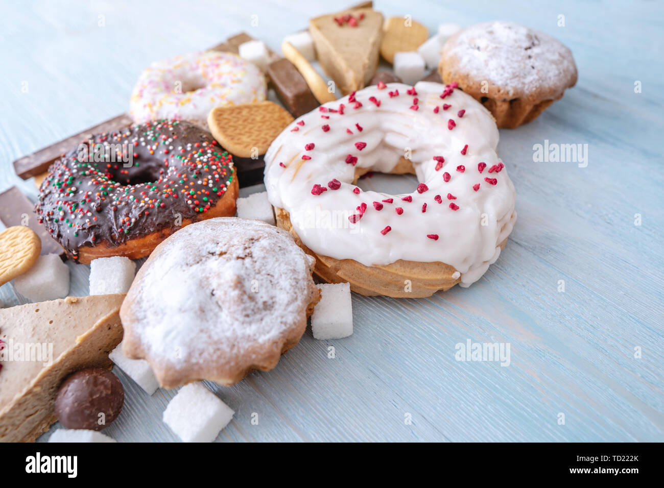 Harmful sweet foods on blue wooden background. Donuts, muffins ...