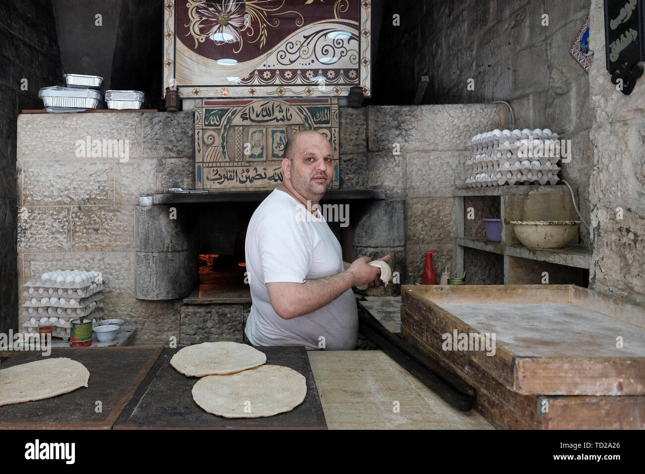 A Palestinian man baking Pita bread in a small bakery located in the ...