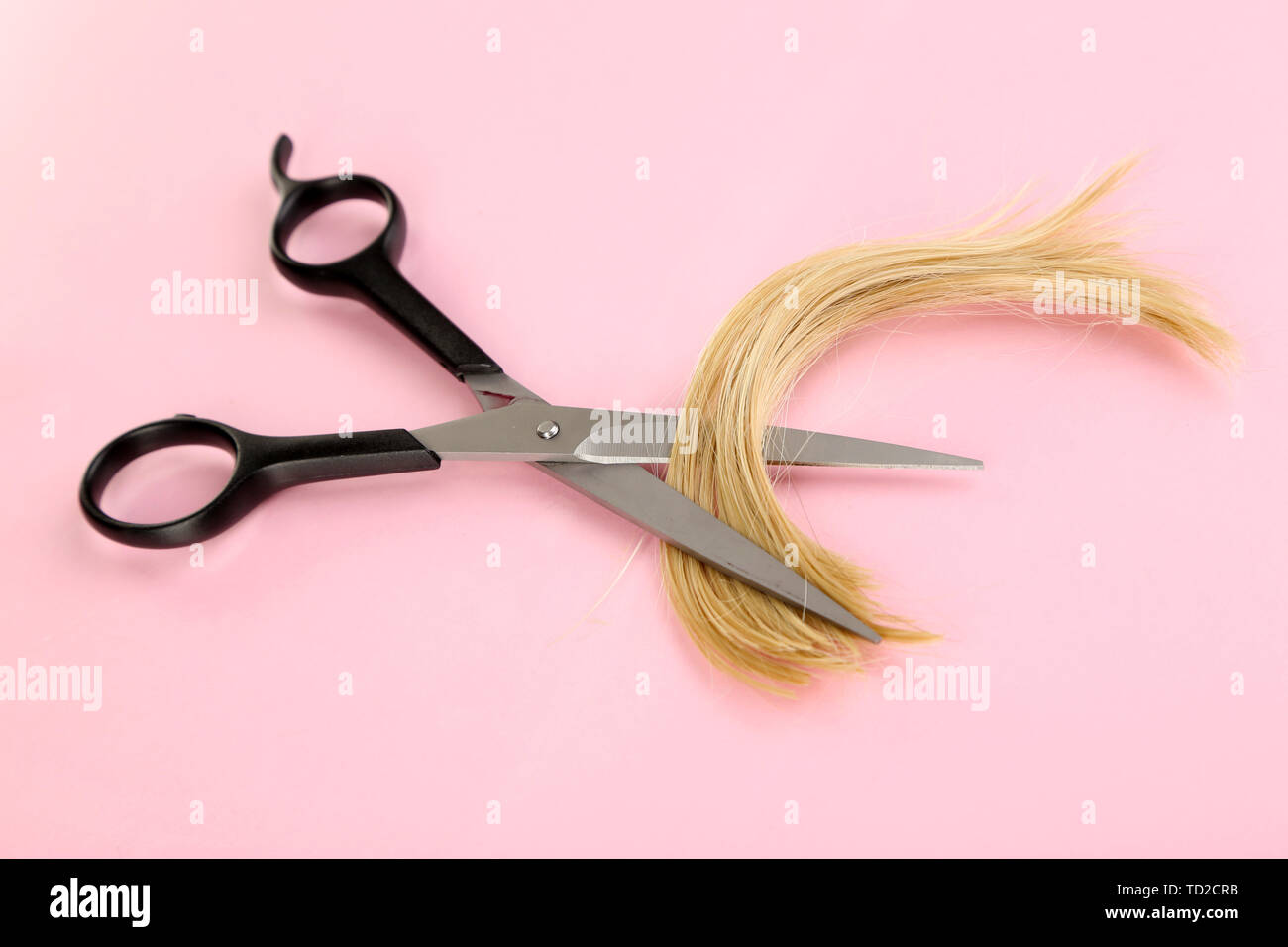 Pieces of hair cut with scissors on pink background Stock Photo - Alamy