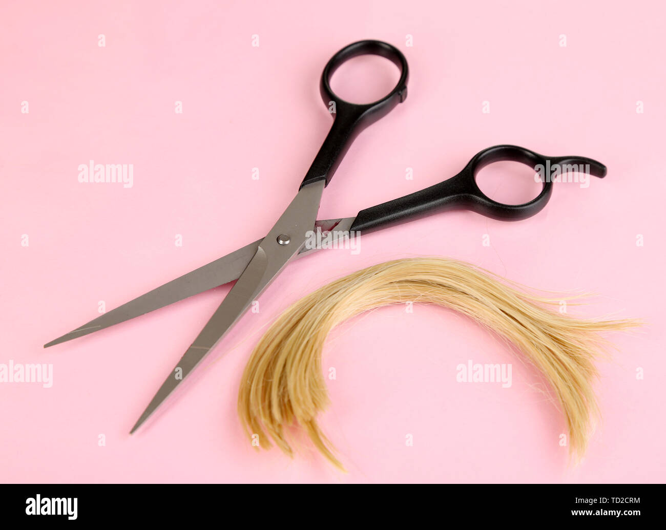 Pieces of hair cut with scissors on pink background Stock Photo - Alamy
