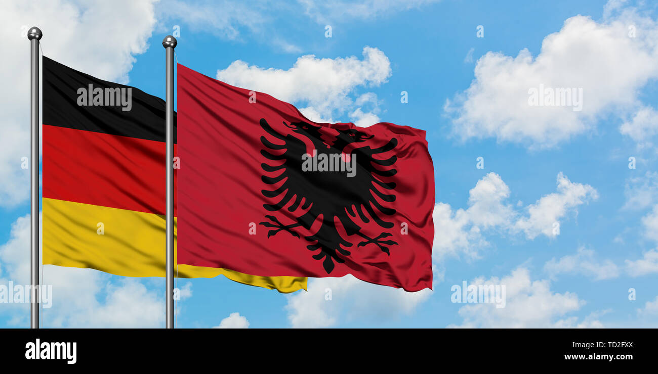 Germany and Albania flag waving in the wind against white cloudy blue ...