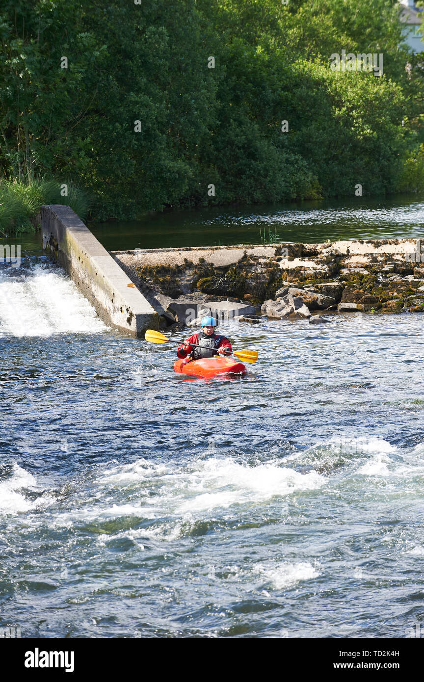 A man white water kayaking in the river Leven at Newby Bridge, South ...