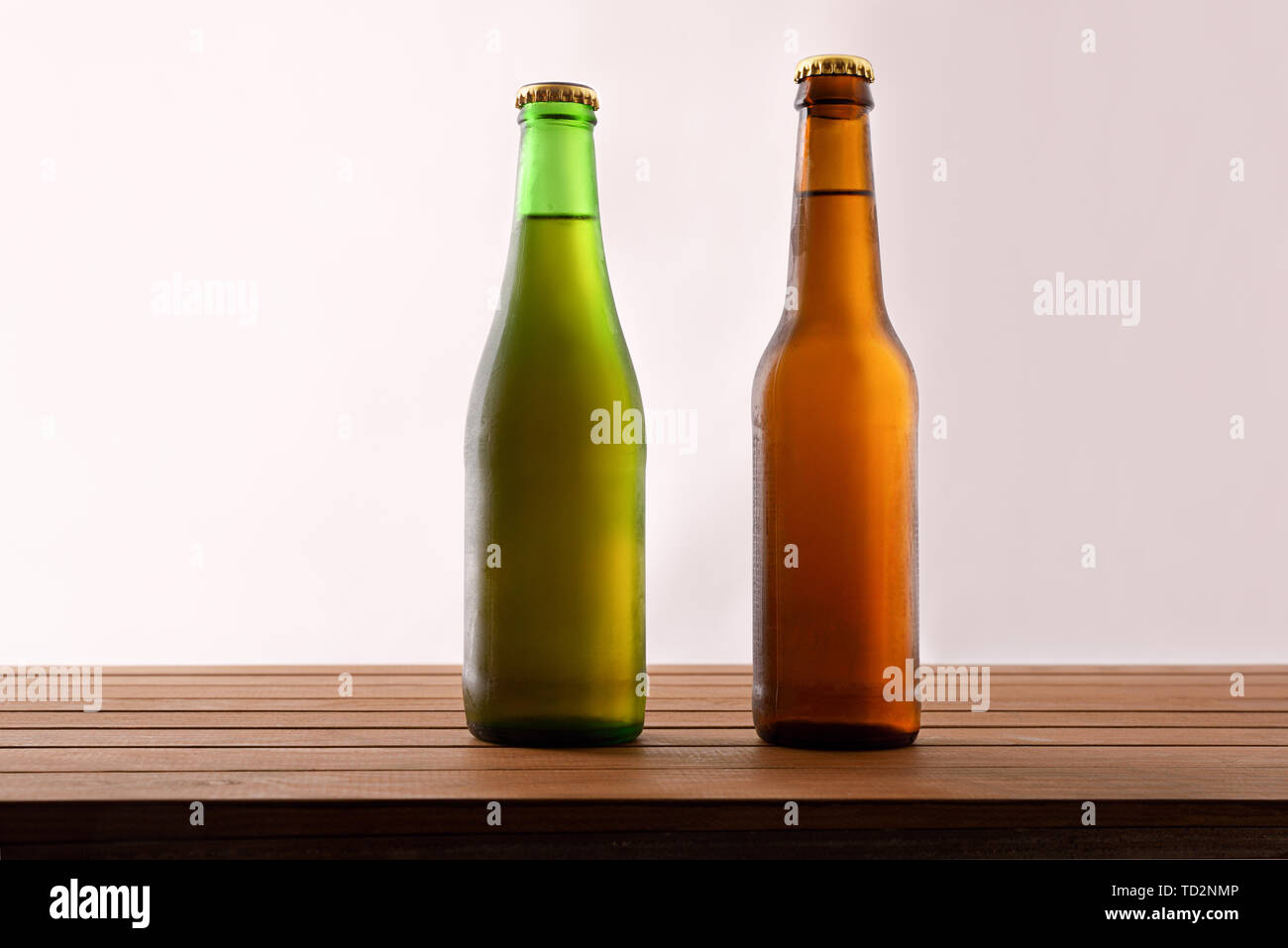 Two different beer bottles filled and closed on wooden table and light ...