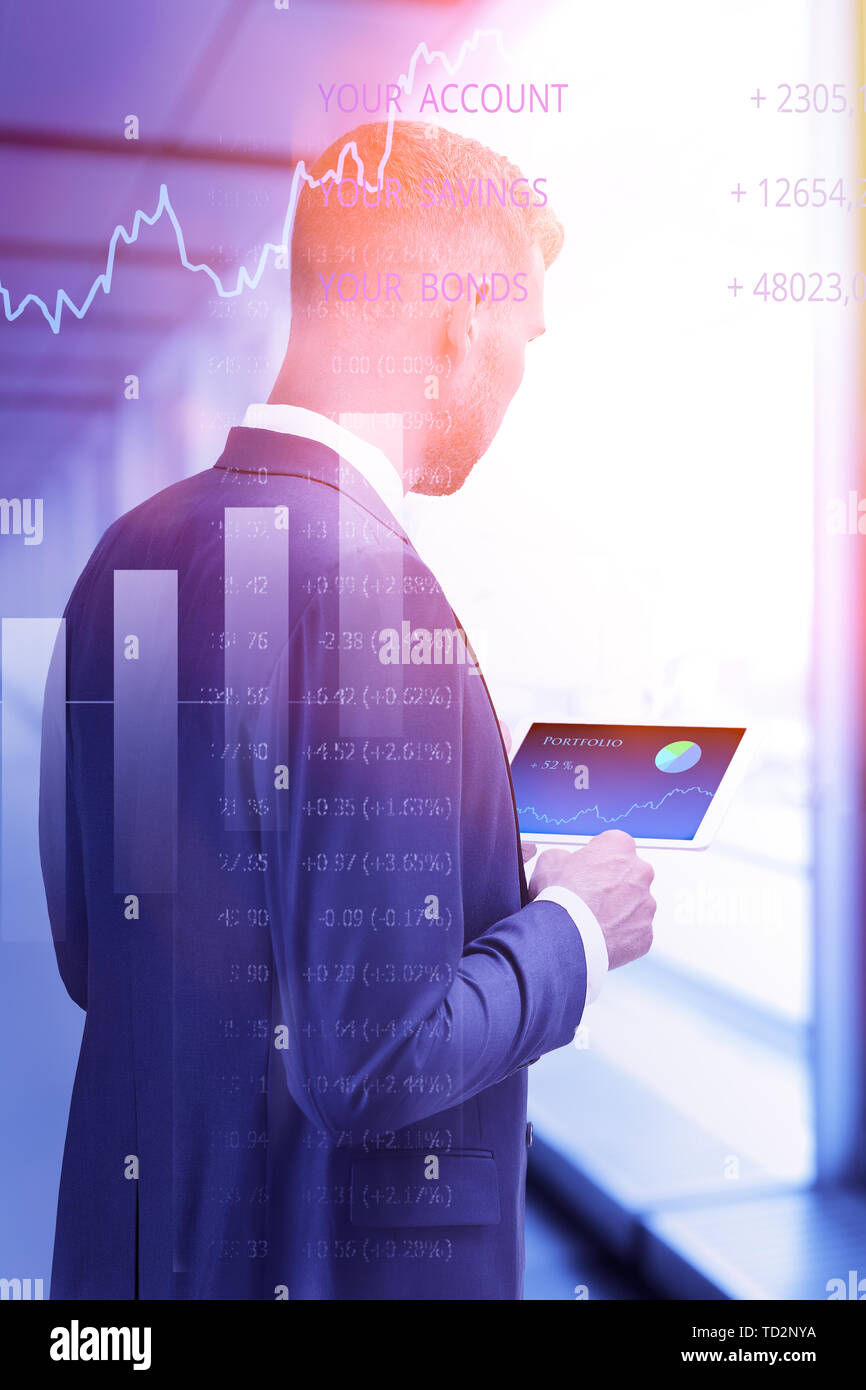 Young man checking his investment portfolio on his tablet computer ...