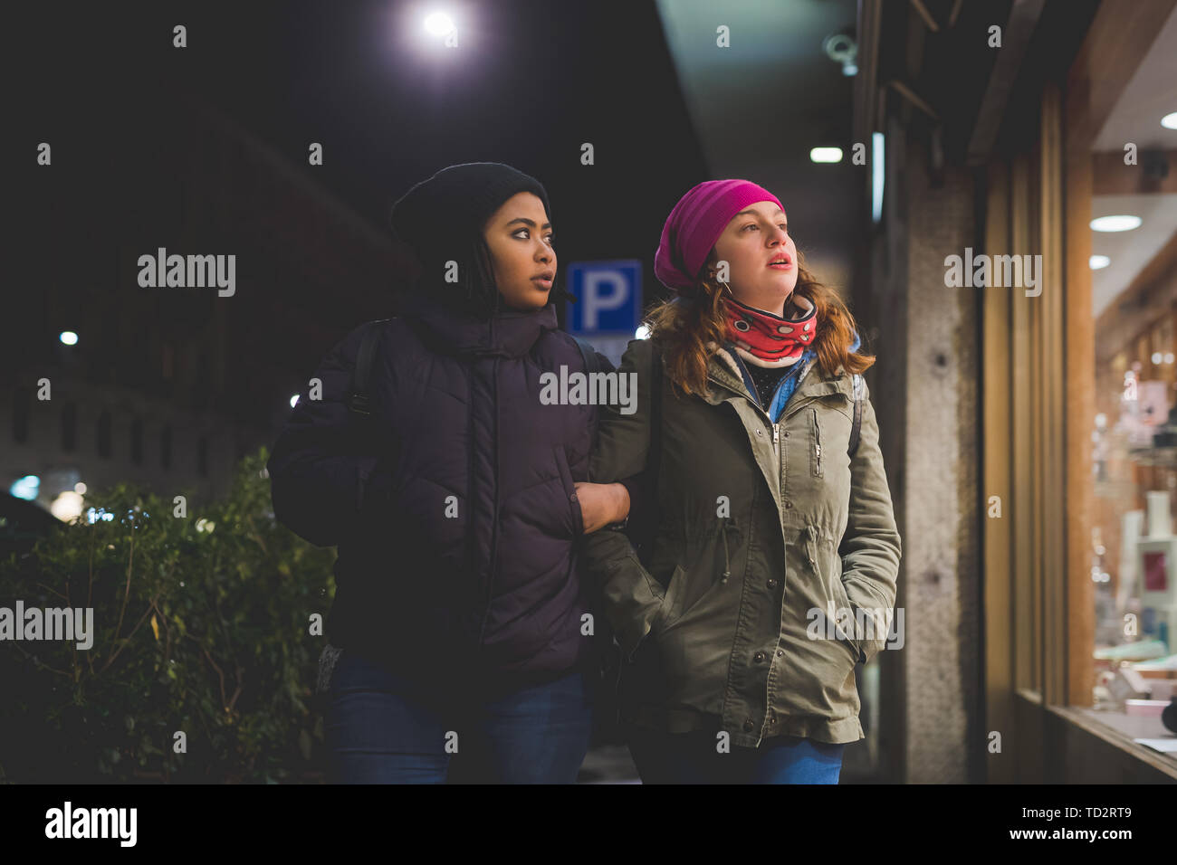 two multiracial women walking in the street and looking shop windows ...