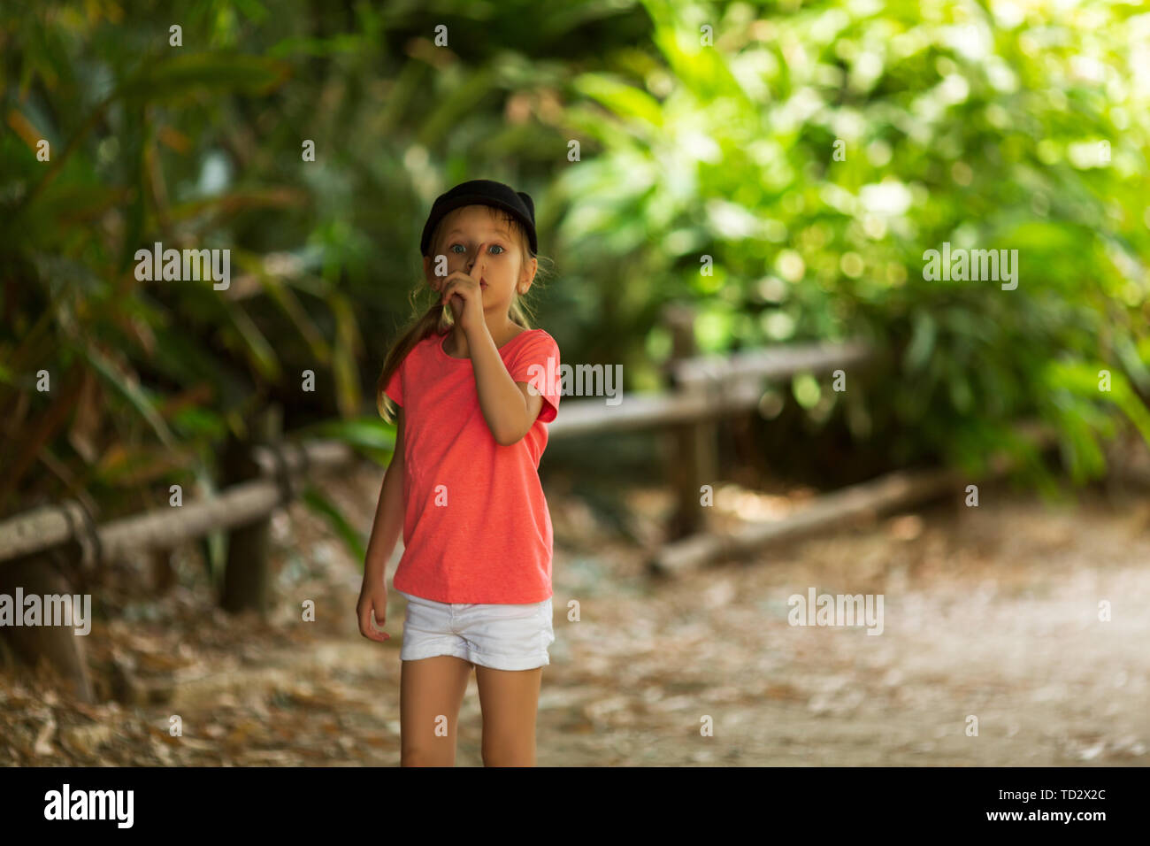 Cute female preschooler walking on path among green garden in summer ...