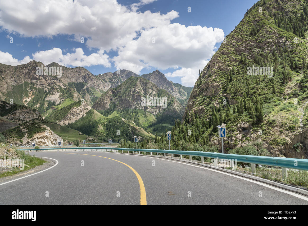 G217 Duku Highway bend in alpine forest under summer blue sky and white ...