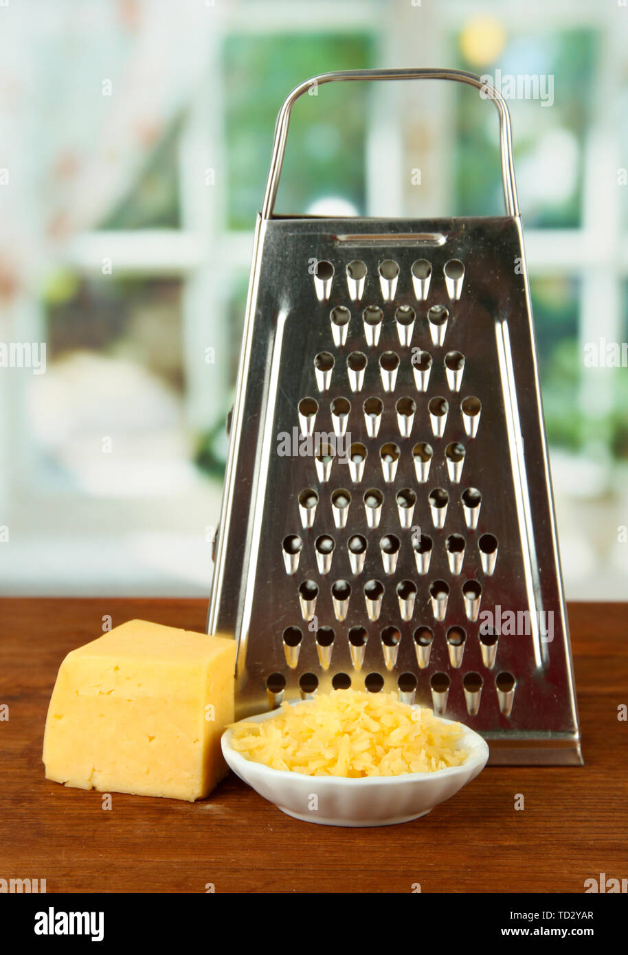 Metal grater and cheese, on bright background Stock Photo - Alamy