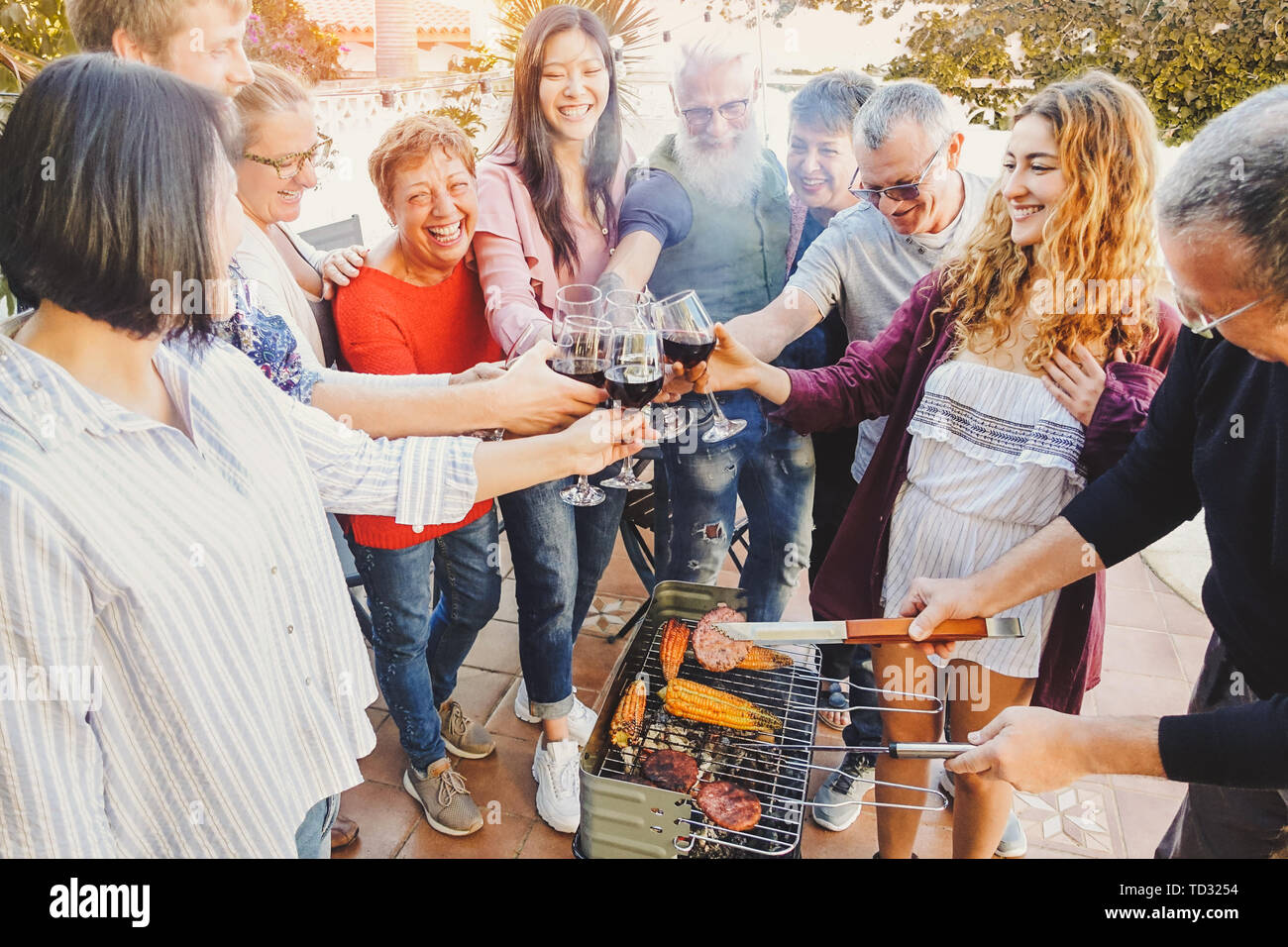 Happy family cheering and toasting with red wine glass at barbecue ...