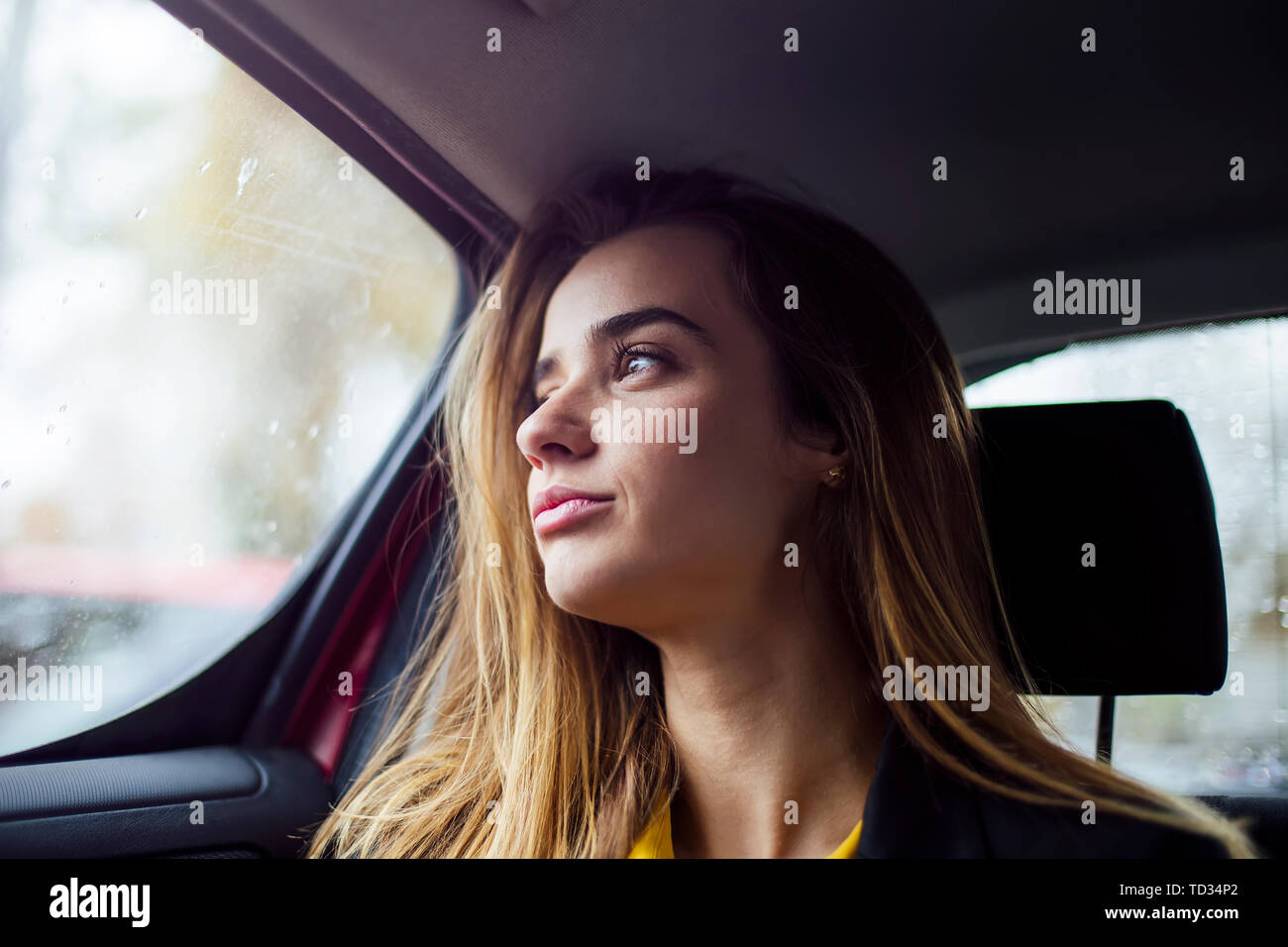 Beautiful pretty young businesswoman sitting on back seat of a car and ...