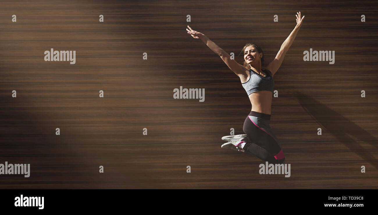 Young sporty girl jumping happily on wooden background outdoor Stock ...