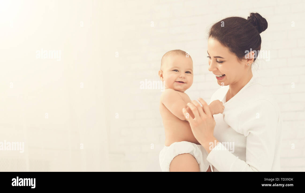 Young mother sitting with baby on bed Stock Photo - Alamy