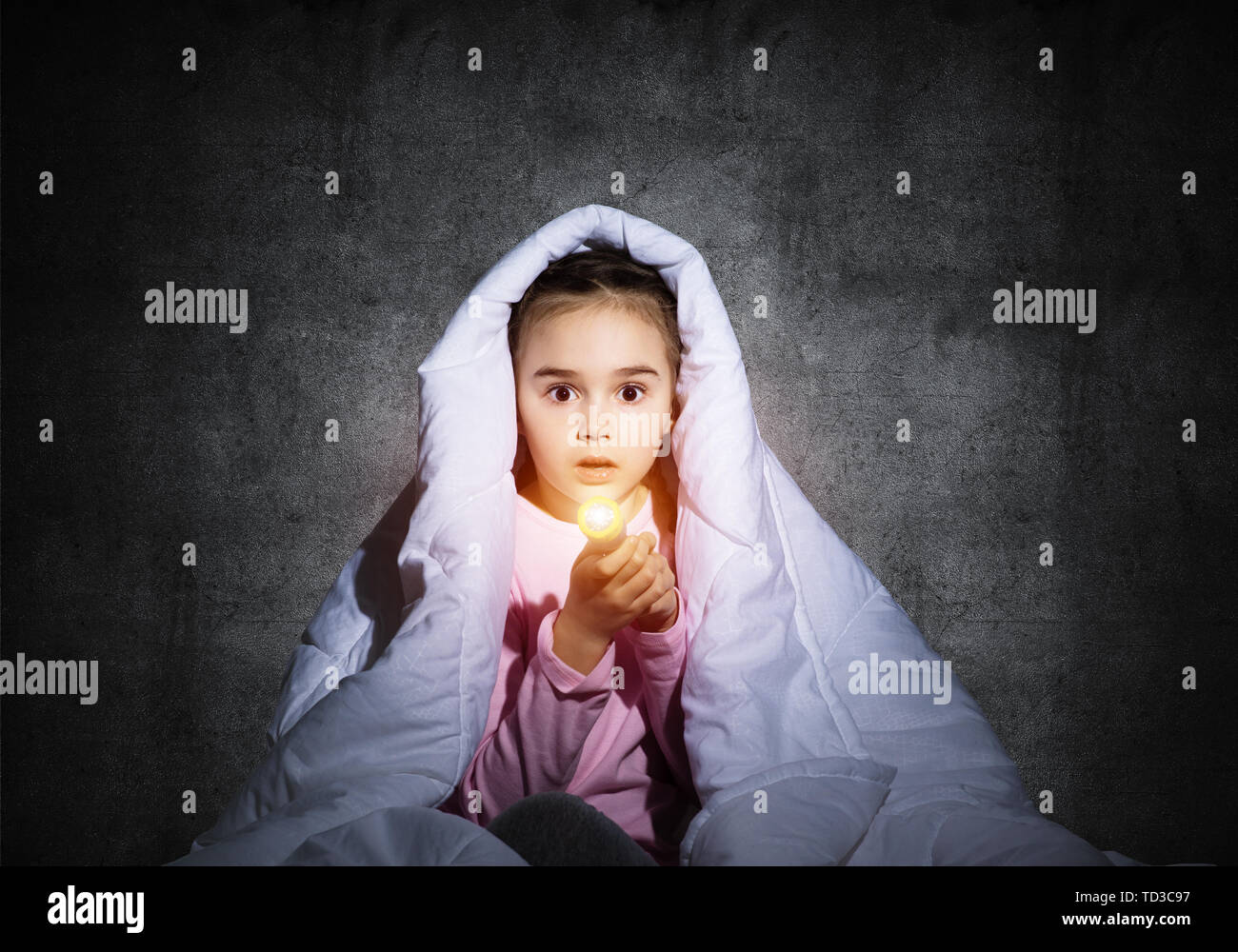 Frightened girl with flashlight under blanket Stock Photo - Alamy