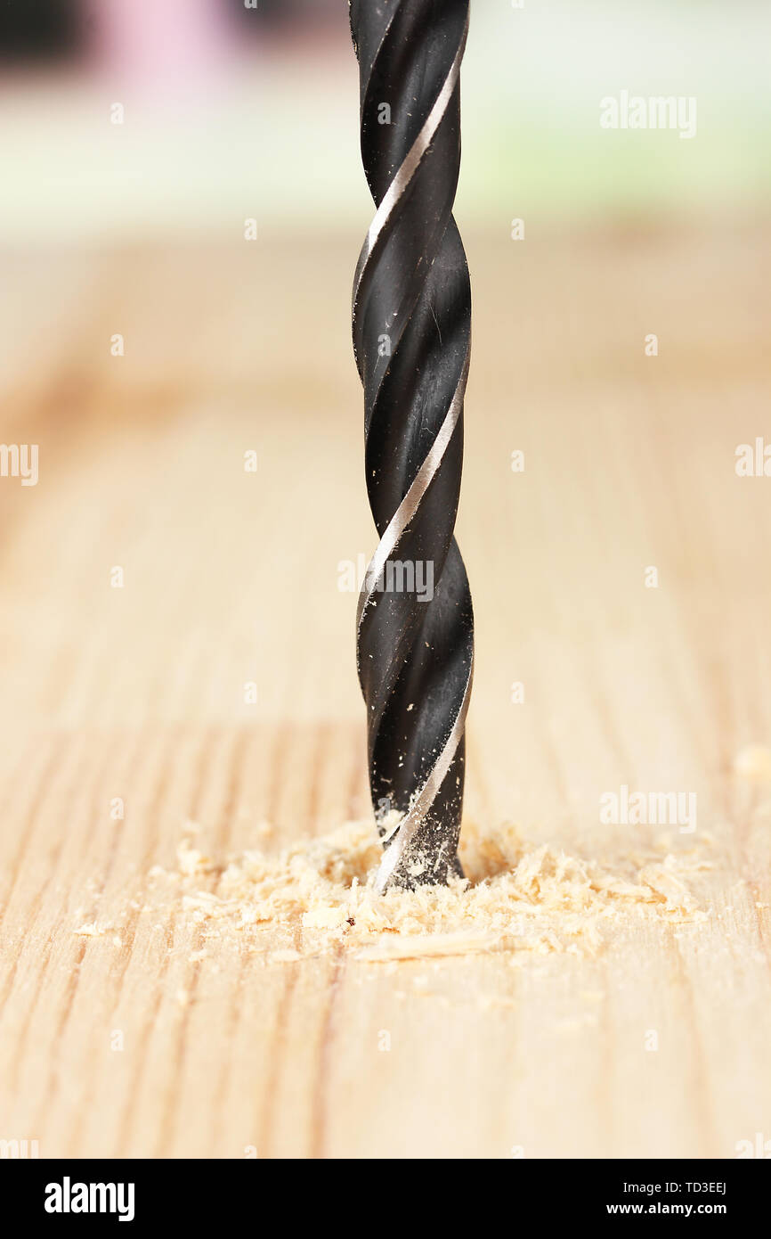 Close-up image of drilling hole on wooden plank, on bright background ...