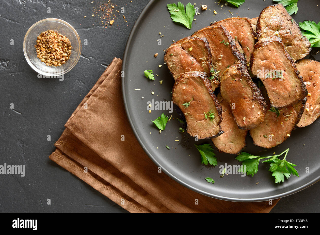 Grilled sliced beef liver on plate over black stone background. Cooked ...