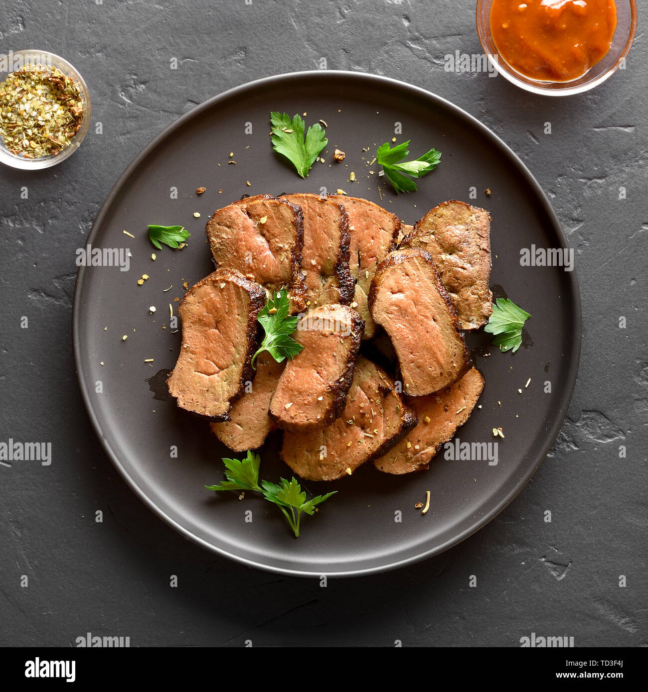 Close up of grilled beef liver on plate over black stone background ...