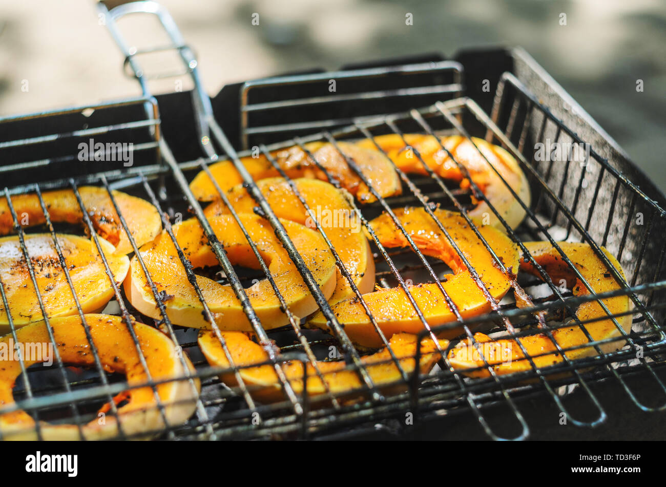 Baked pumpkin slices on the grill grid. The process of cooking ...