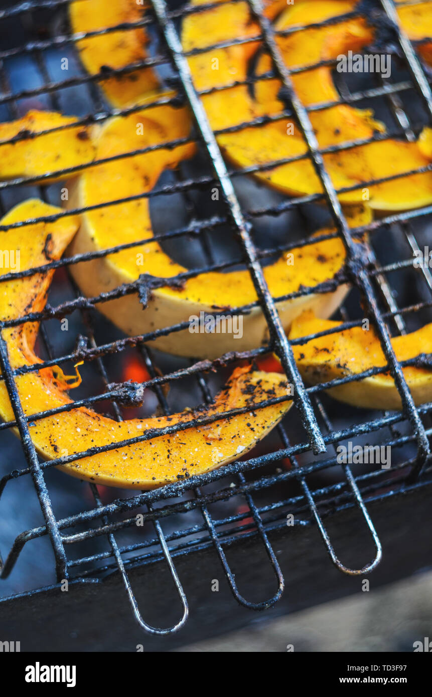 Baked pumpkin slices on the grill grid. The process of cooking ...