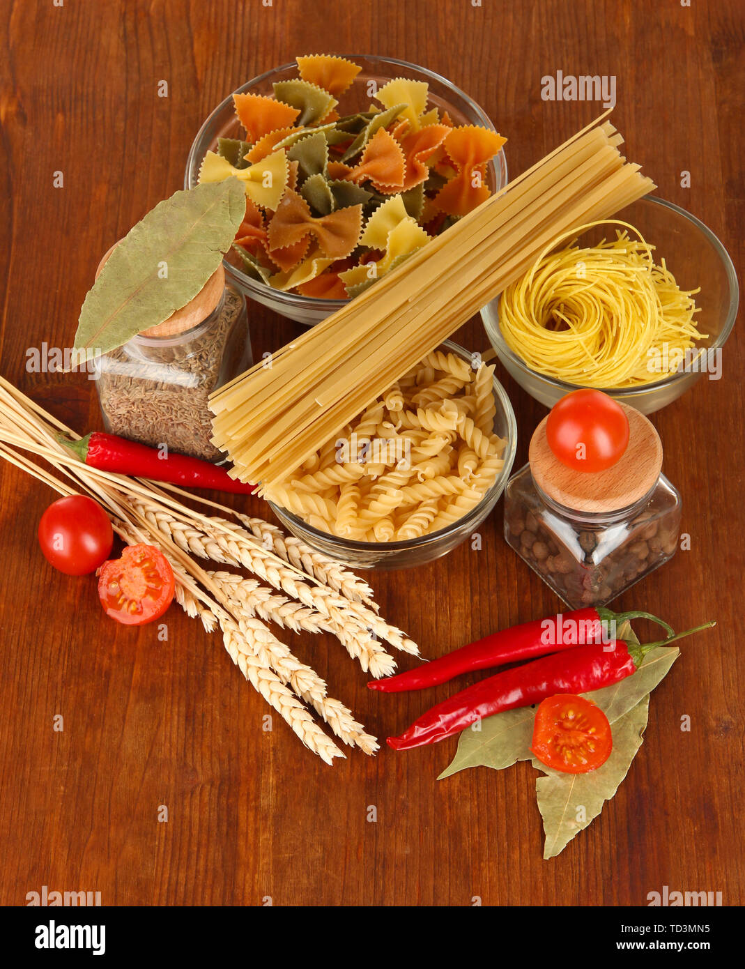 Different types of pasta, spices, tomatoes on a wooden table Stock ...