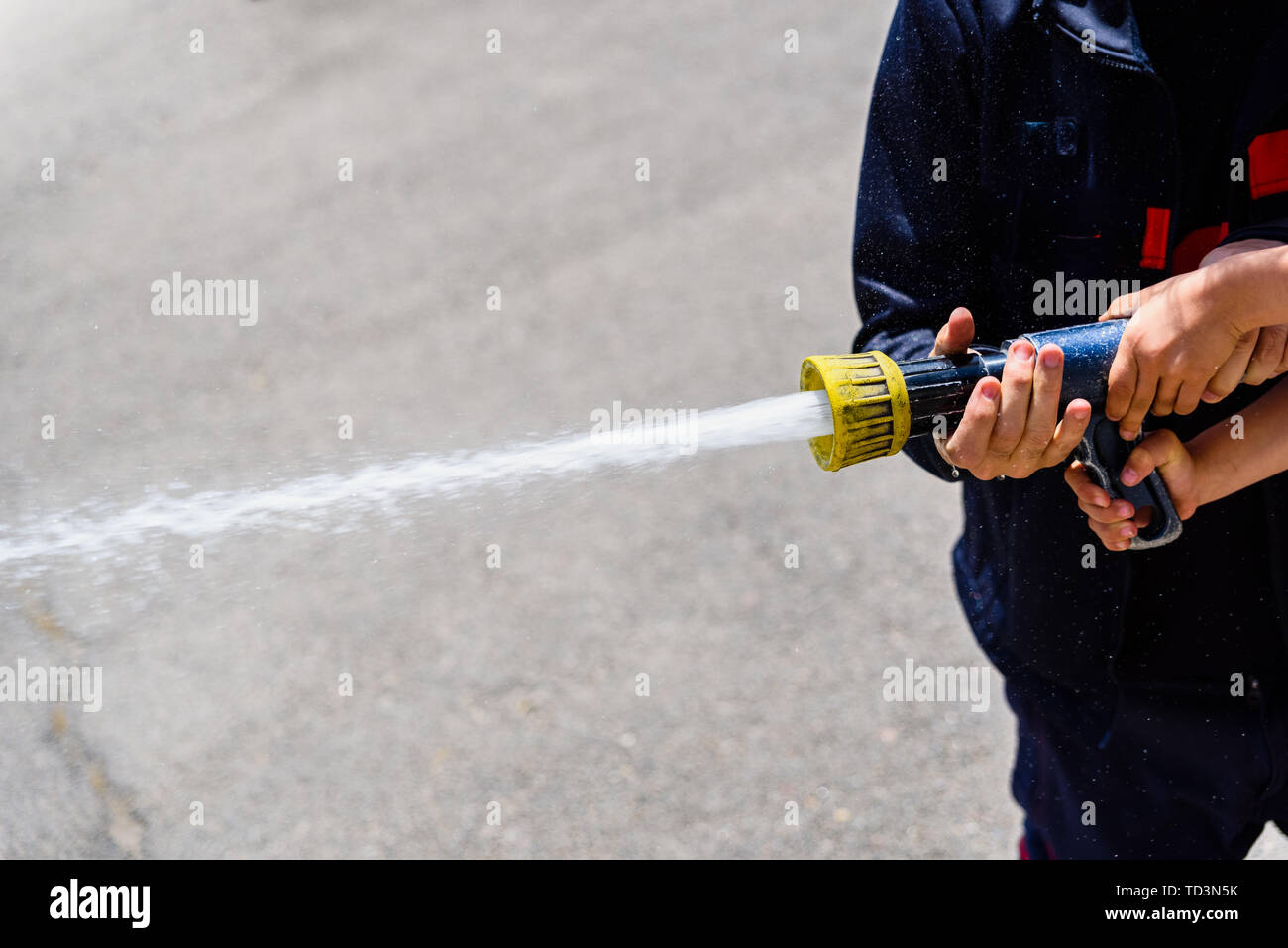 Firefighter demonstrating how to use a water hose to children during a ...