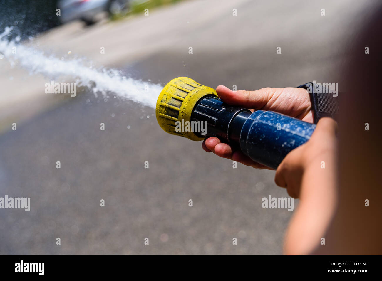 Hands of firefighter, no face, holding a hose by throwing water at high ...