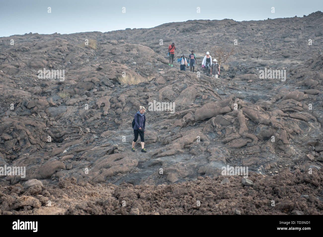 Tourists traversing the precarious terrain of the Erta Ale Volcano, a ...
