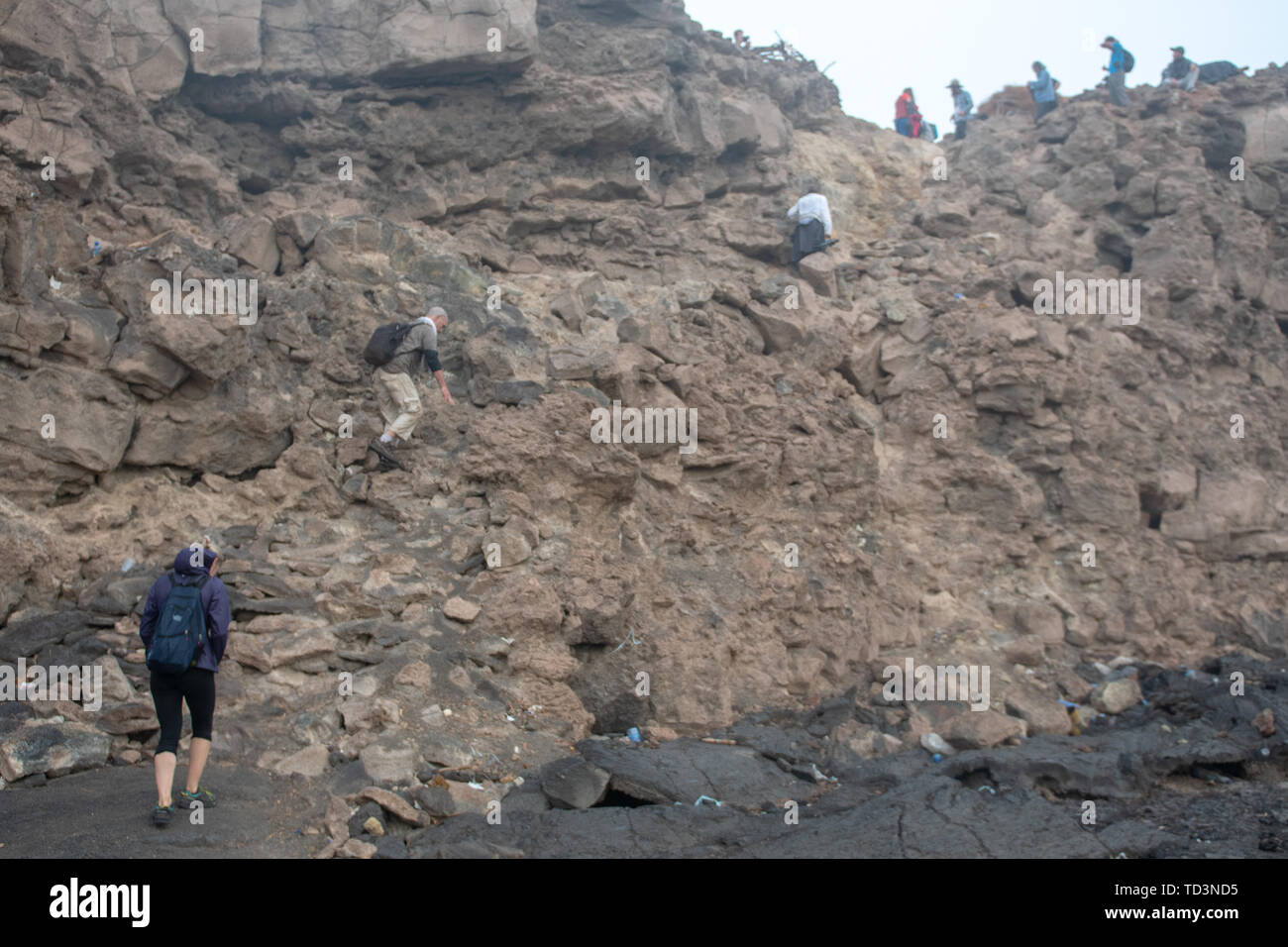 Tourists traversing the precarious terrain of the Erta Ale Volcano, a ...