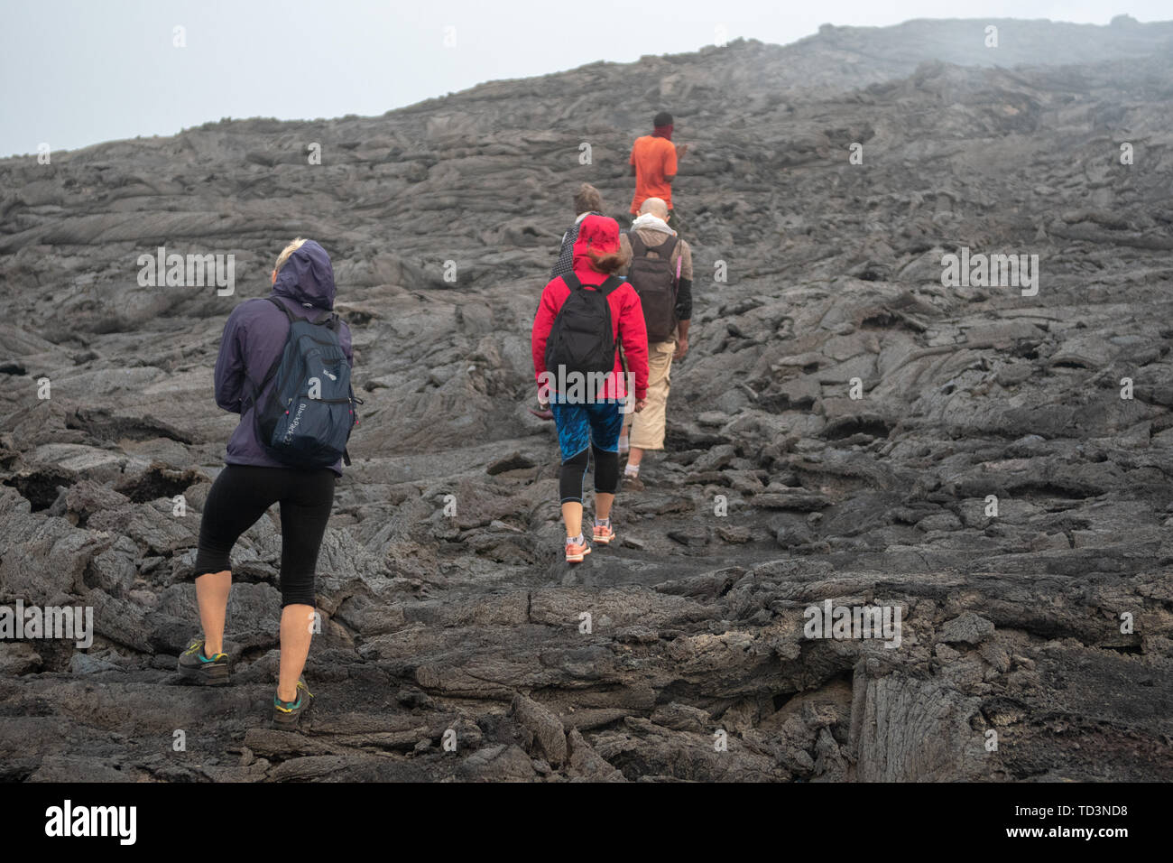 Tourists traversing the precarious terrain of the Erta Ale Volcano, a ...
