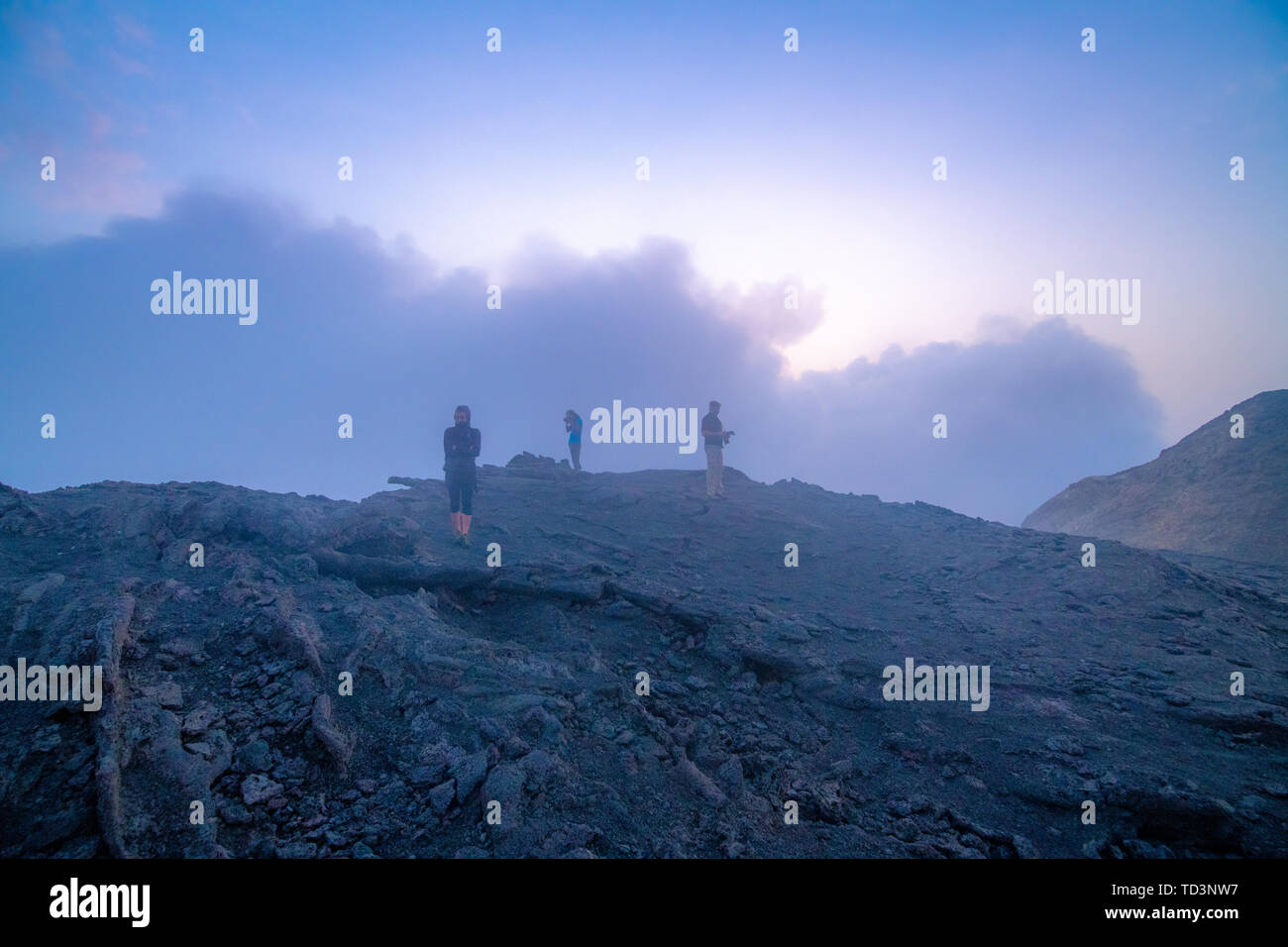 Tourists traversing the precarious terrain of the Erta Ale Volcano, a ...