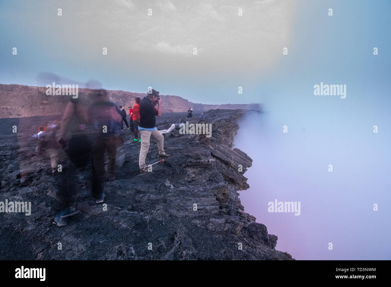 Tourists traversing the precarious terrain of the Erta Ale Volcano, a ...