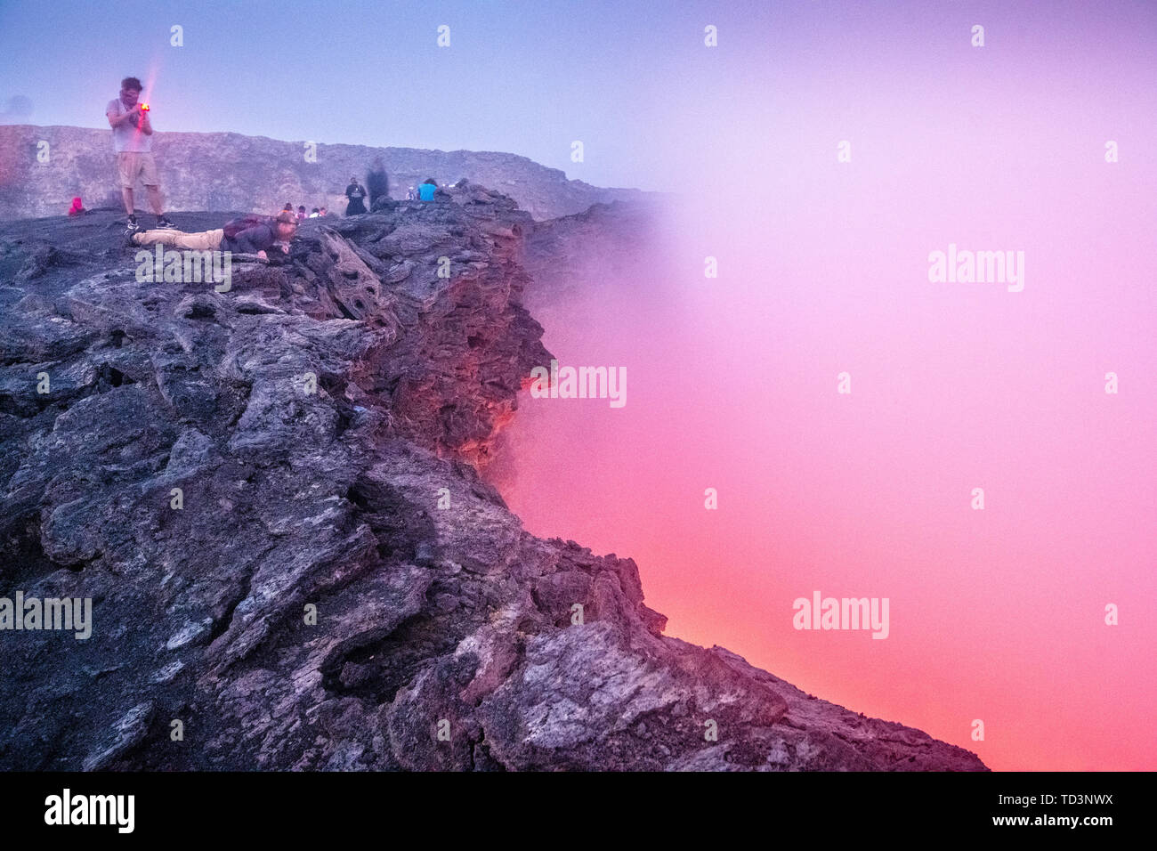 Tourists traversing the precarious terrain of the Erta Ale Volcano, a ...