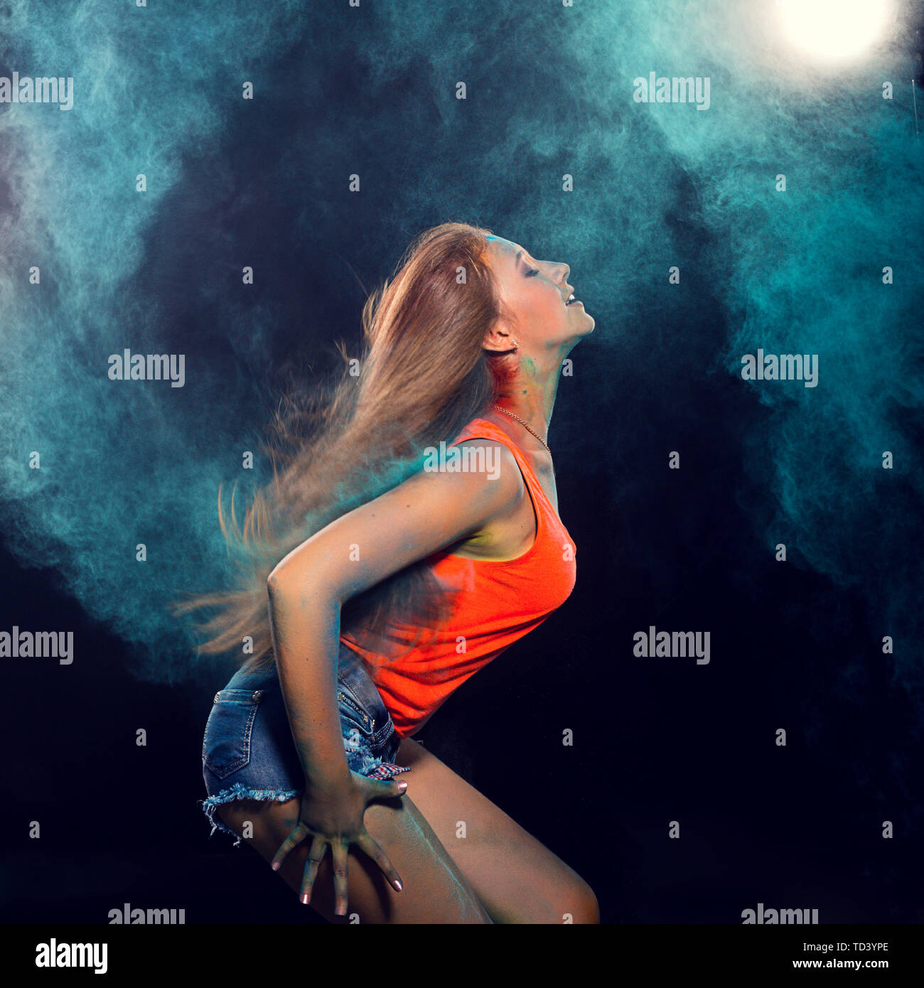 girl with colored powder trailing behind her hair that she is flinging ...