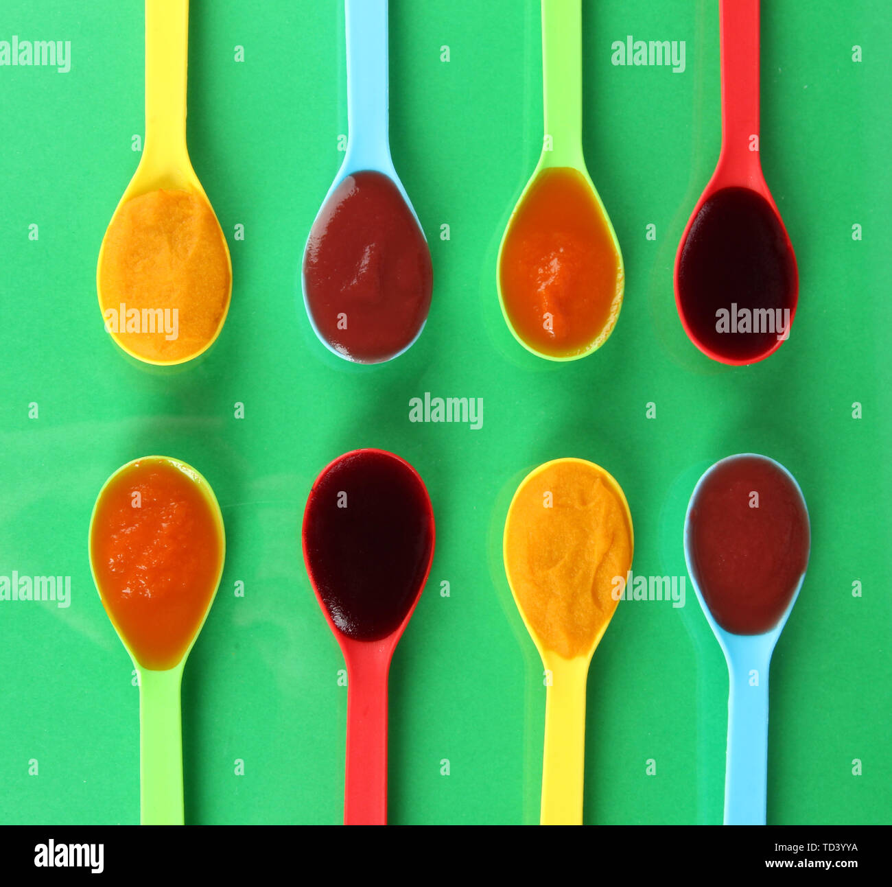Baby puree in spoons on green background Stock Photo - Alamy