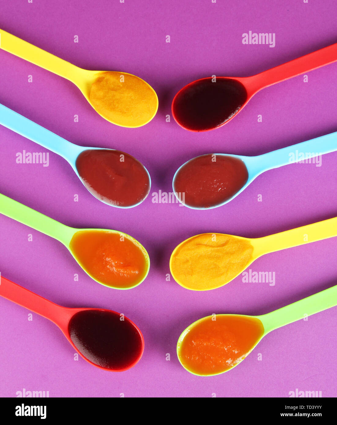Baby puree in spoons on purple background Stock Photo - Alamy