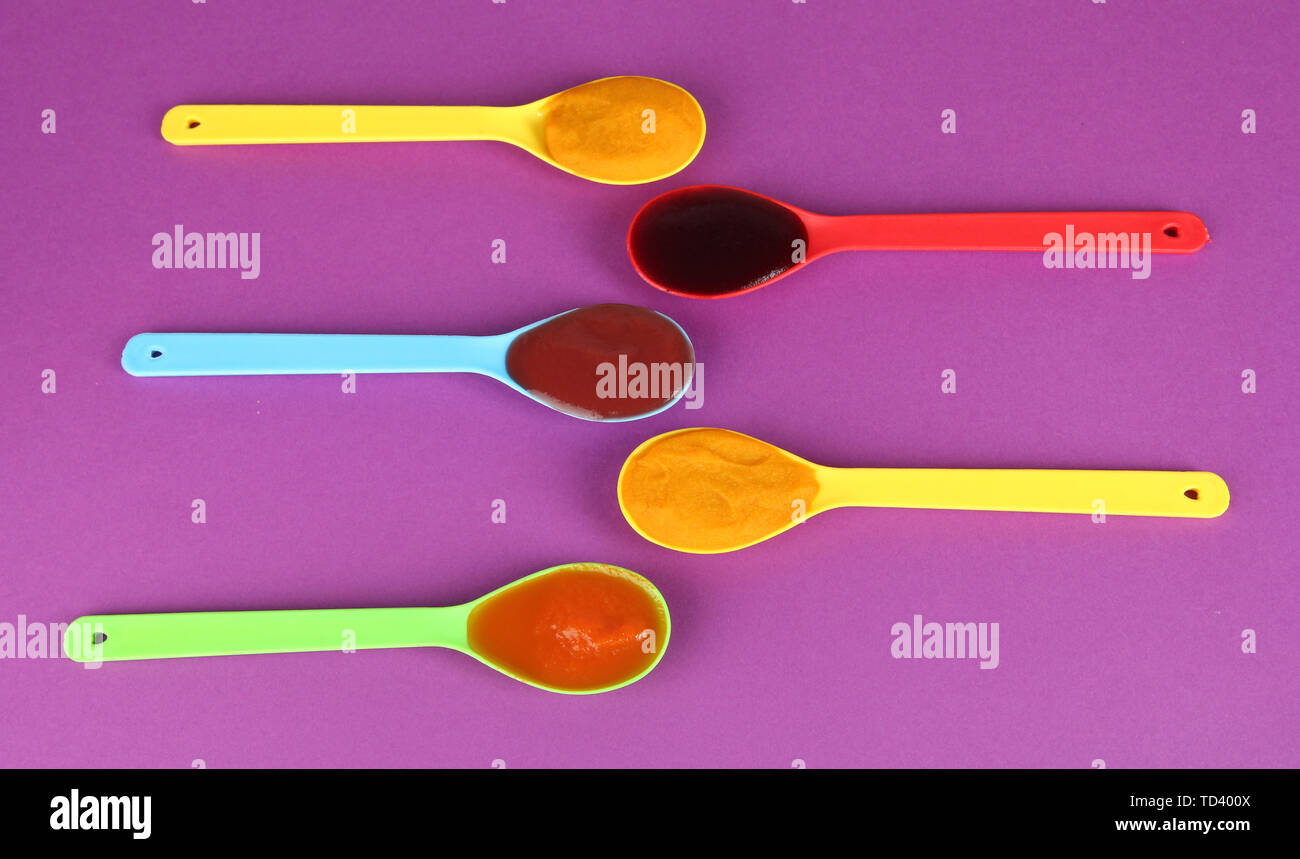 Baby puree in spoons on purple background Stock Photo - Alamy