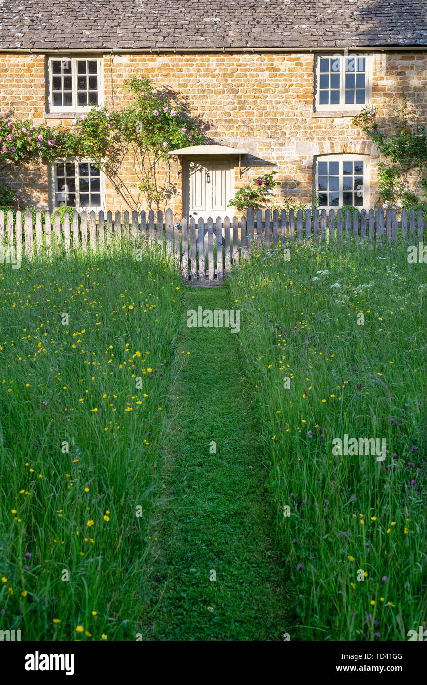 Mown path through long grass to a Cotswold stone cottage. Wyck ...