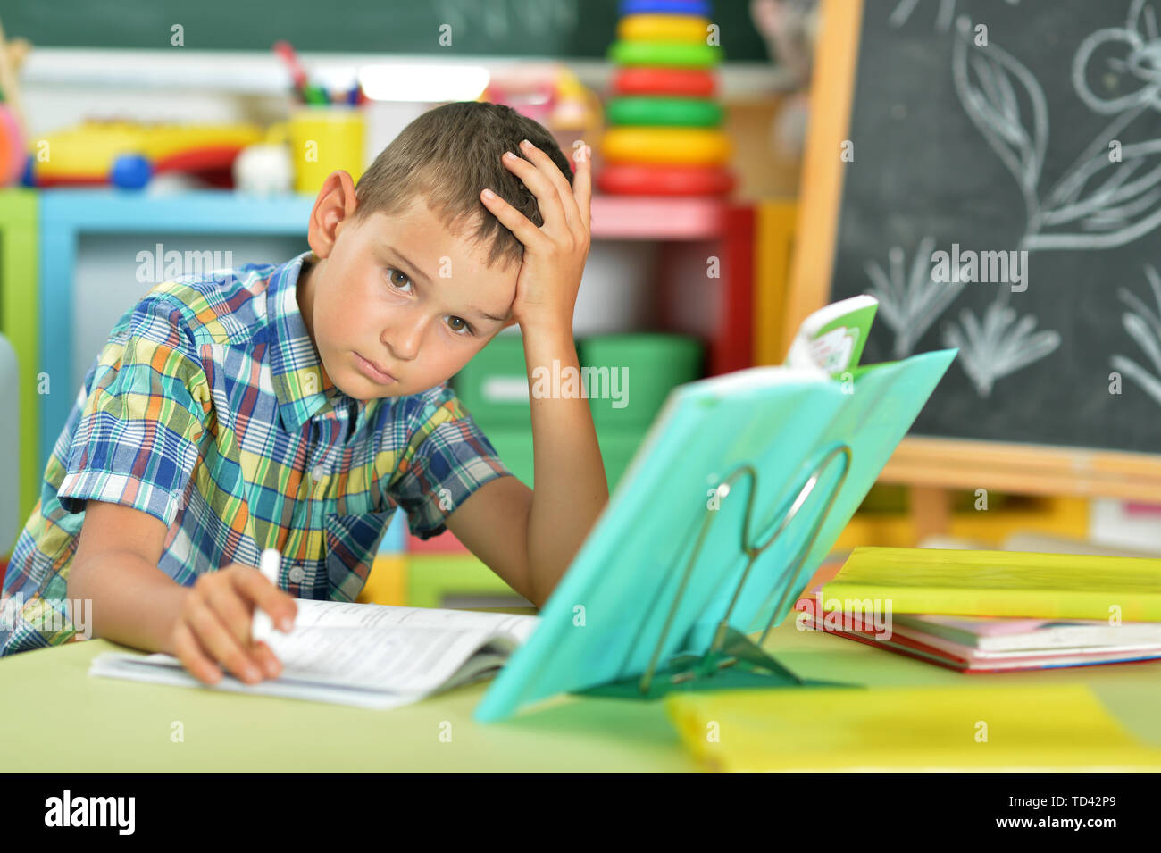 Portrait of tired schoolboy doing homework in classroom Stock Photo - Alamy