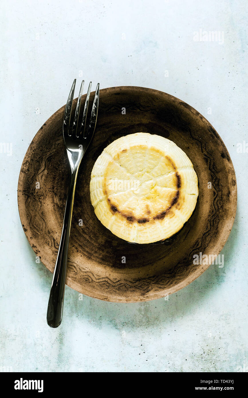Oven baked ricotta cheese on a clay plate and fork. basic cooking ...