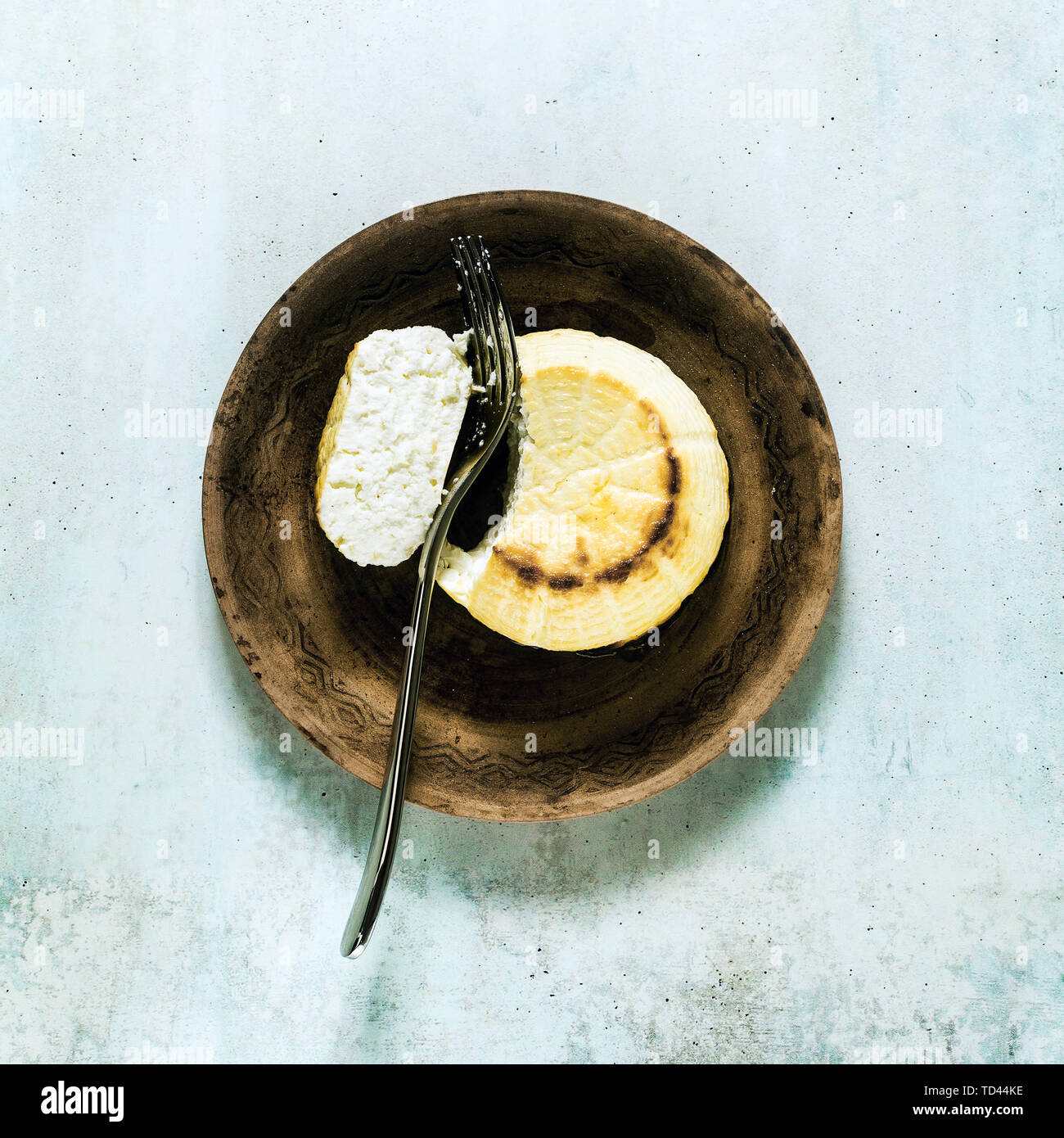 Oven baked ricotta cheese on a clay plate and fork. basic cooking ...