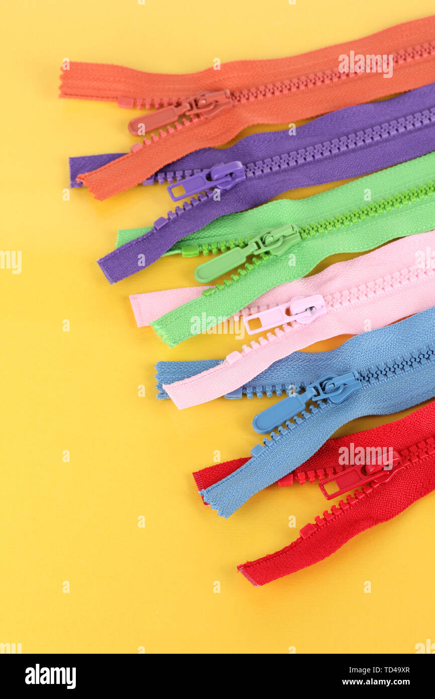 Multicolored zippers on yellow background Stock Photo - Alamy