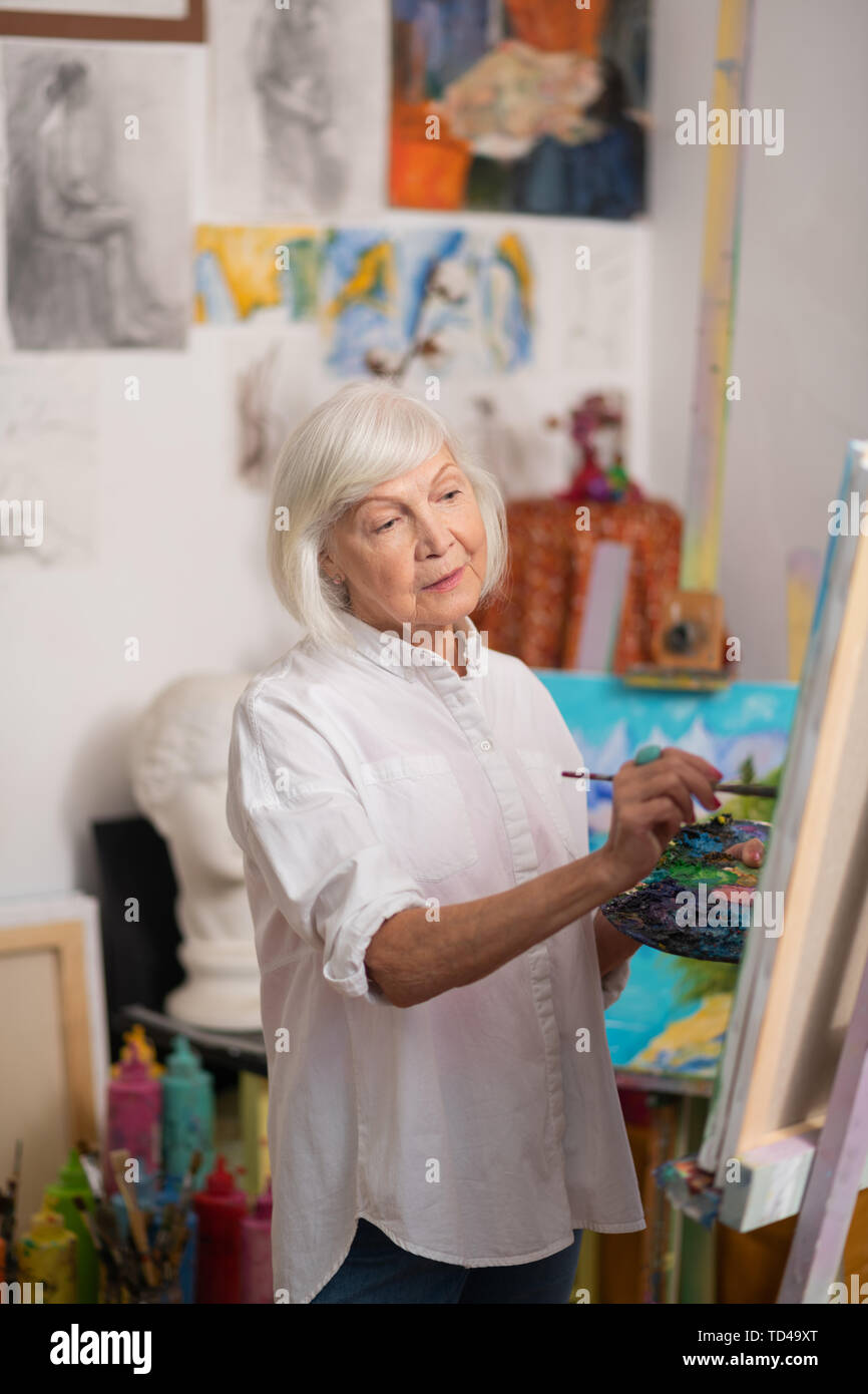 Enjoying her hobby. Aged talented creative woman standing near drawing ...