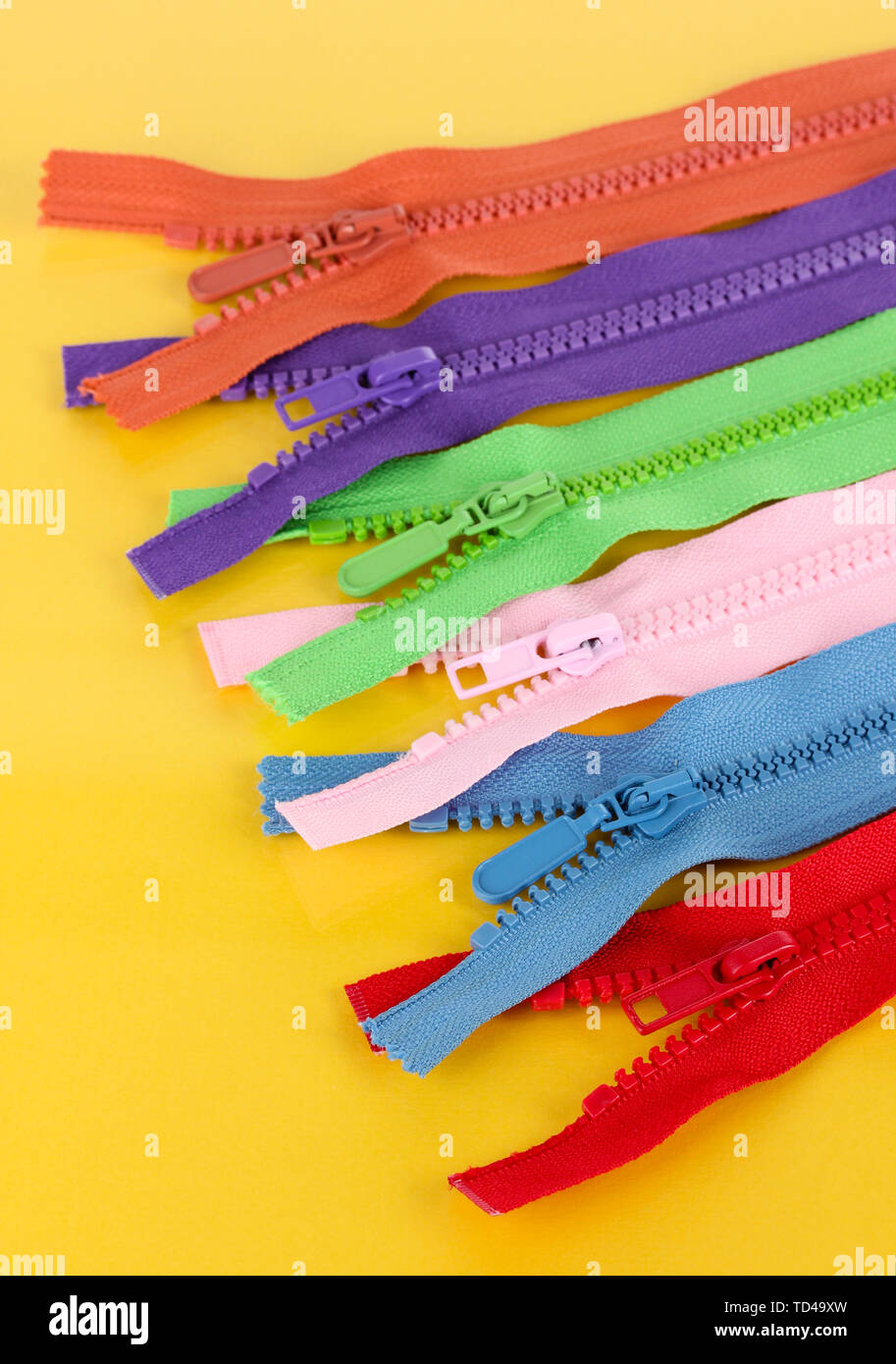 Multicolored zippers on yellow background Stock Photo - Alamy