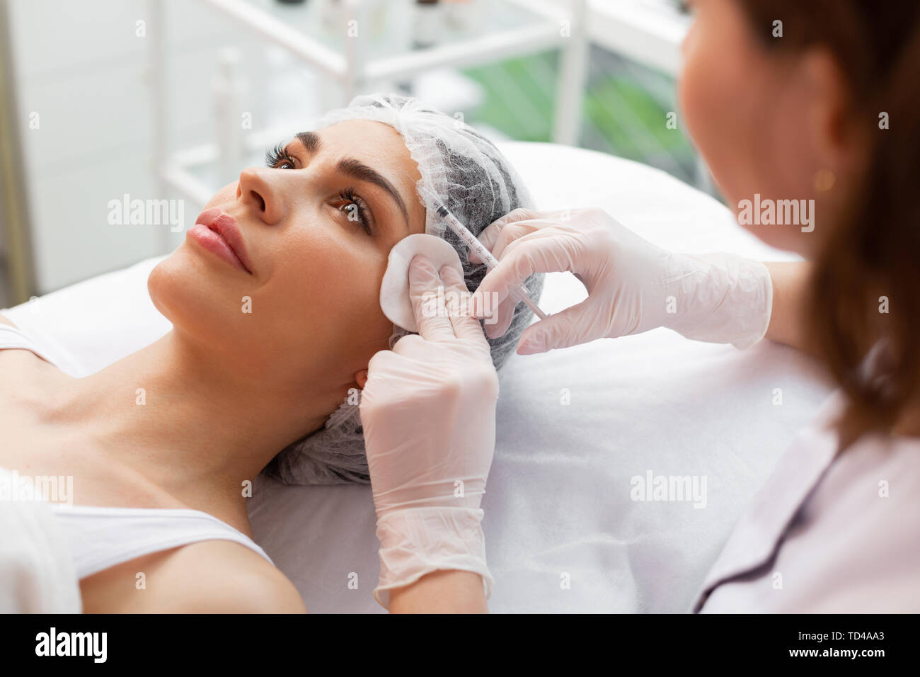 No wrinkles. Professional skilled dermatologist holding a syringe while ...