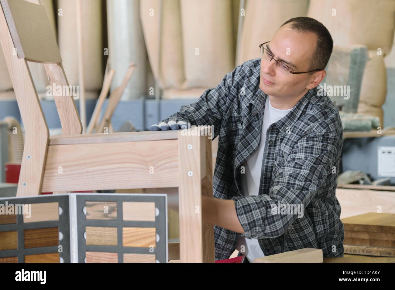 Male carpenter working in furniture joinery, master making wooden chair ...