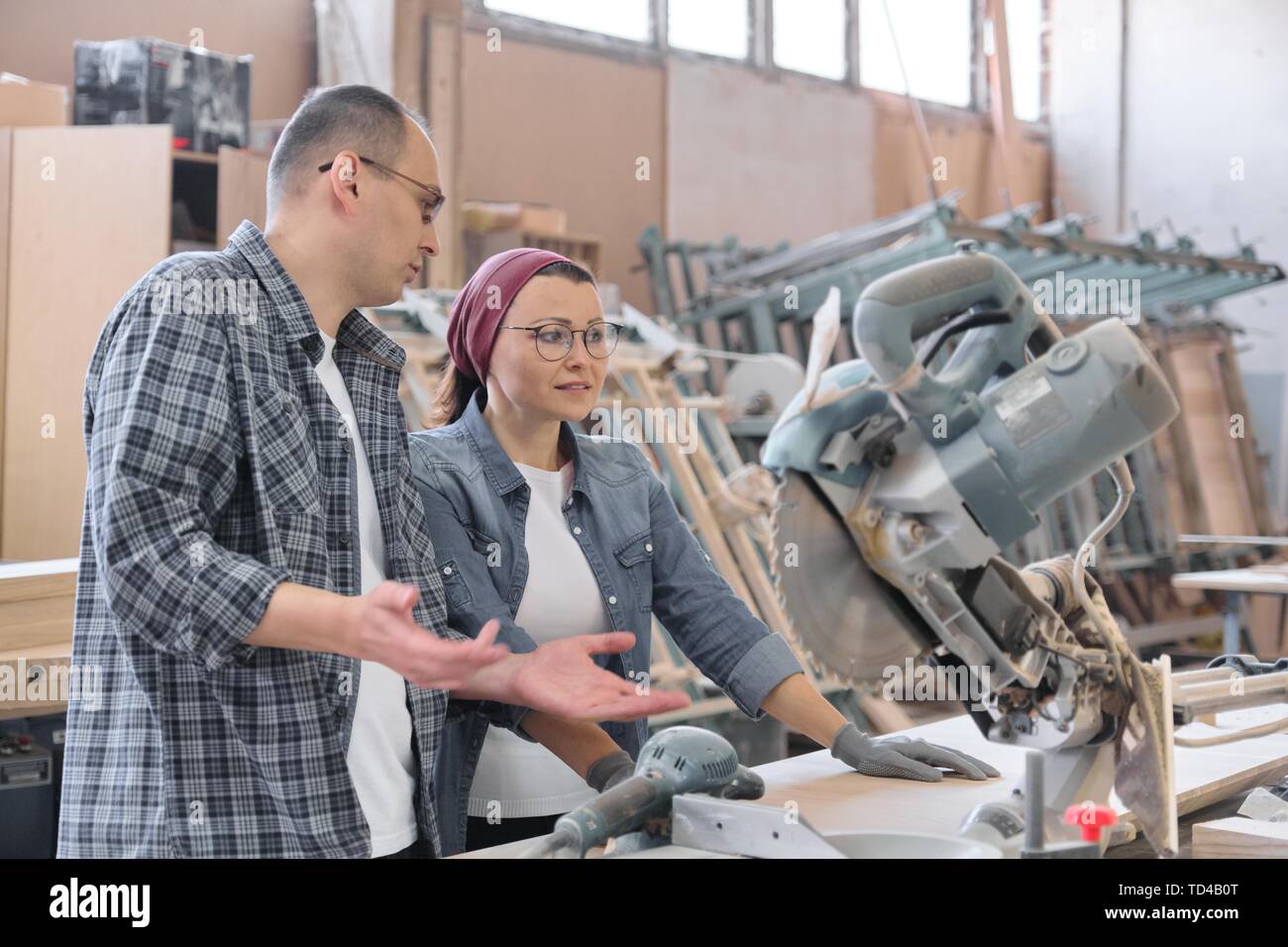 Industrial portrait of two working men and woman, talking at machine ...