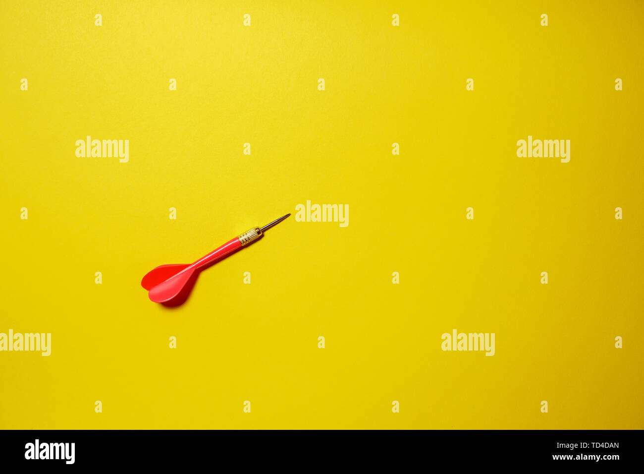 Single red arrow dart isolated on yellow background Stock Photo - Alamy