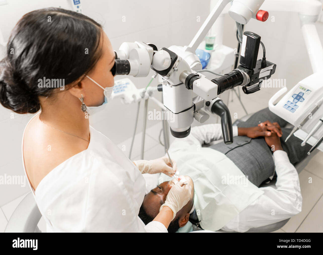 Young woman dentist treating root canals using microscope in the dental ...